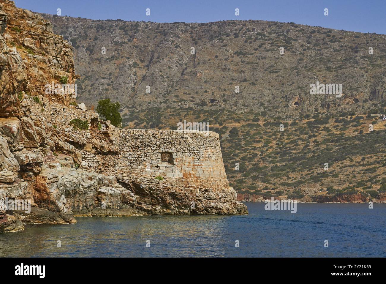 Ancient fortress in rocky coastal landscape surrounded by hilly terrain ...