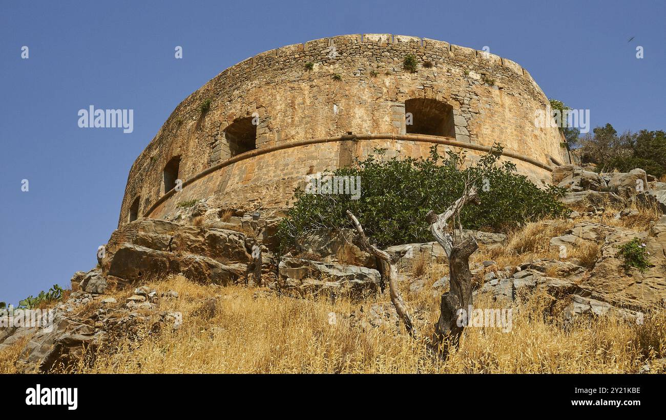 An old round tower on a rocky hill with overgrown vegetation and a ...