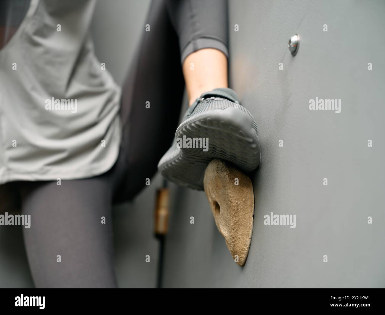 Climber s foot gripping a rock climbing hold on a grey climbing wall ...