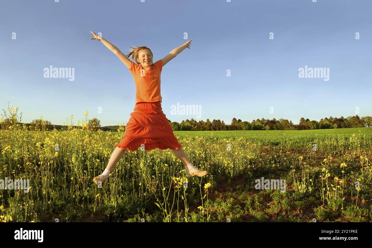 Happy and girl in a meadow, jumping into air Stock Photo - Alamy