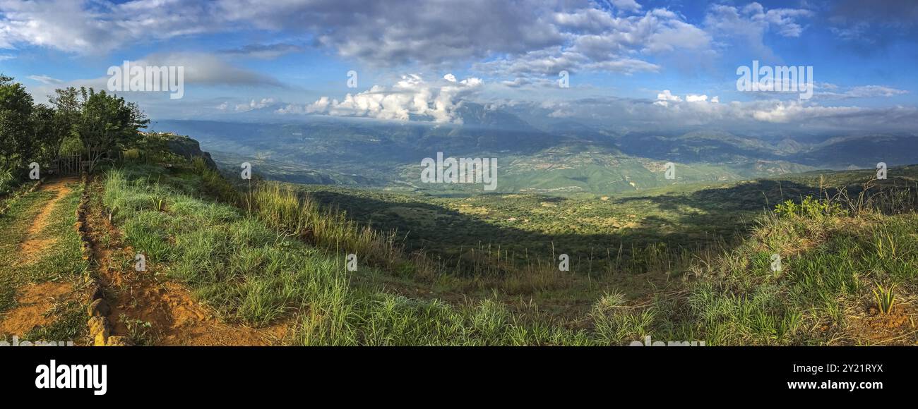 Panorama over the cliffs into a green valley and mountains in sun and ...
