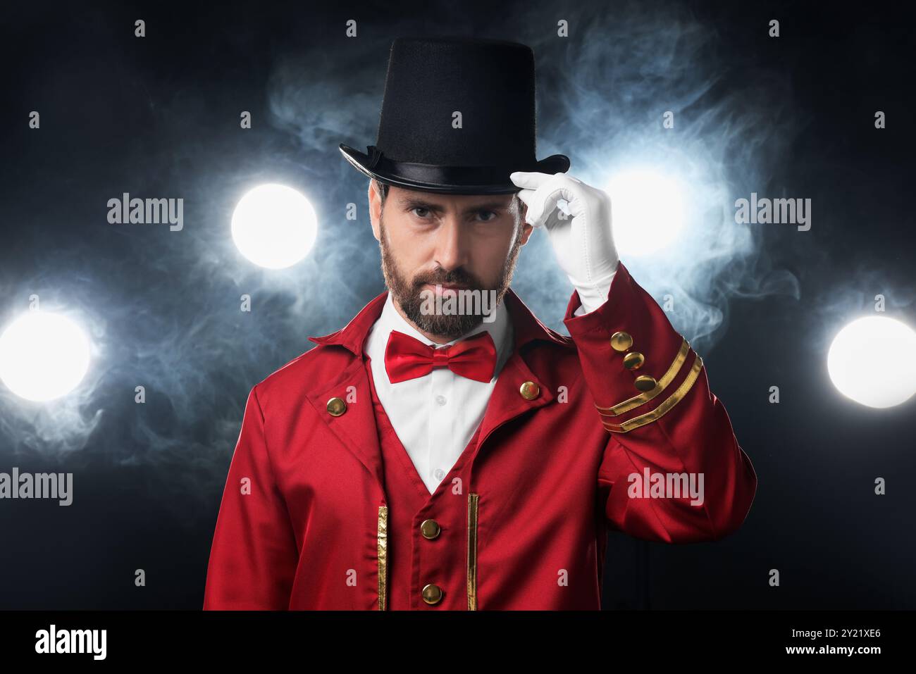 Portrait of showman in red costume and hat on black background with ...