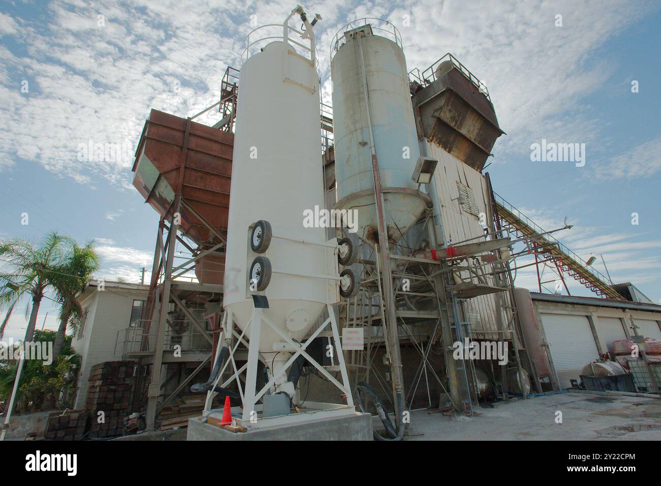 Wide view up to blue sky and white clouds of a concrete mixing plant ...