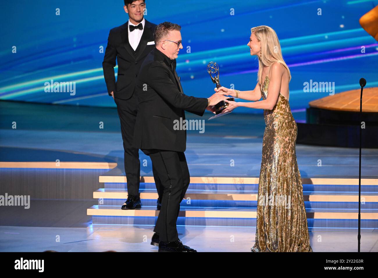 Desi Lydic, from right, presents Michael Cliett with the Emmy for ...