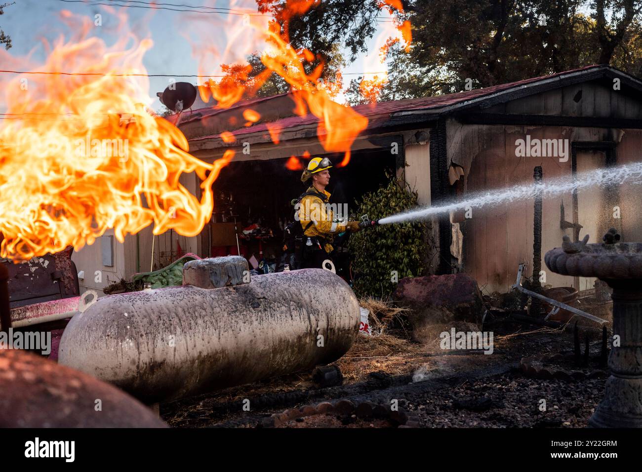 Firefighter Nolan Graham sprays water around a scorched garage as the ...