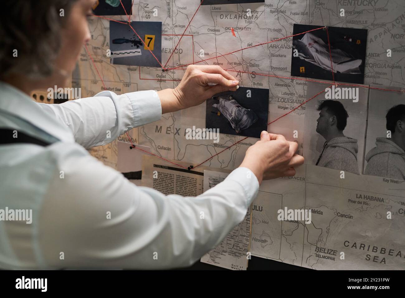 Investigative professional analyzing a detailed board with photographs ...
