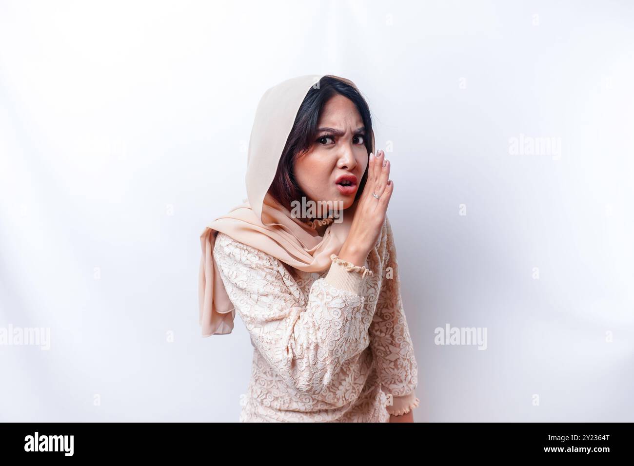 Young beautiful Asian Muslim woman wearing a hijab shouting and ...