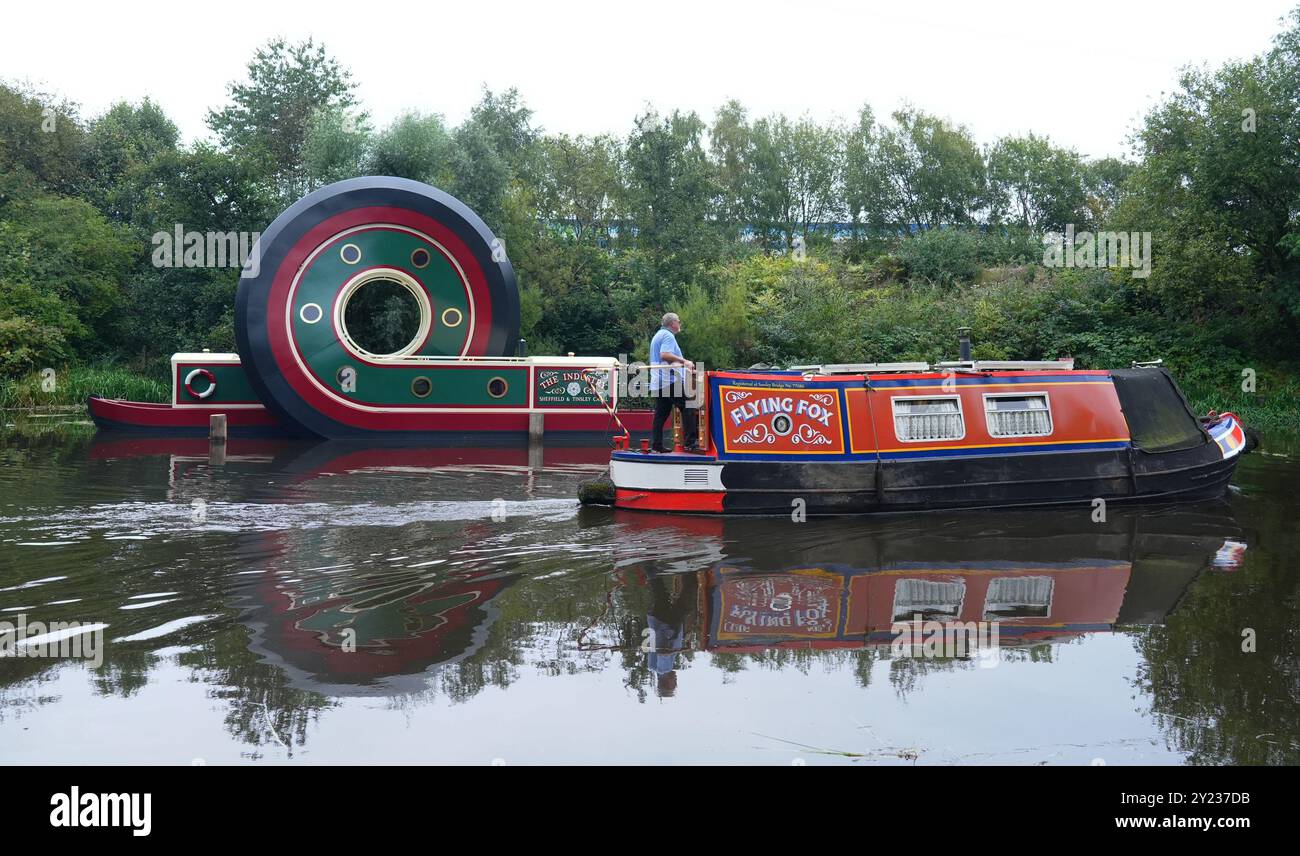 A canal boat passes the new sculpture of a canal boat after it was ...