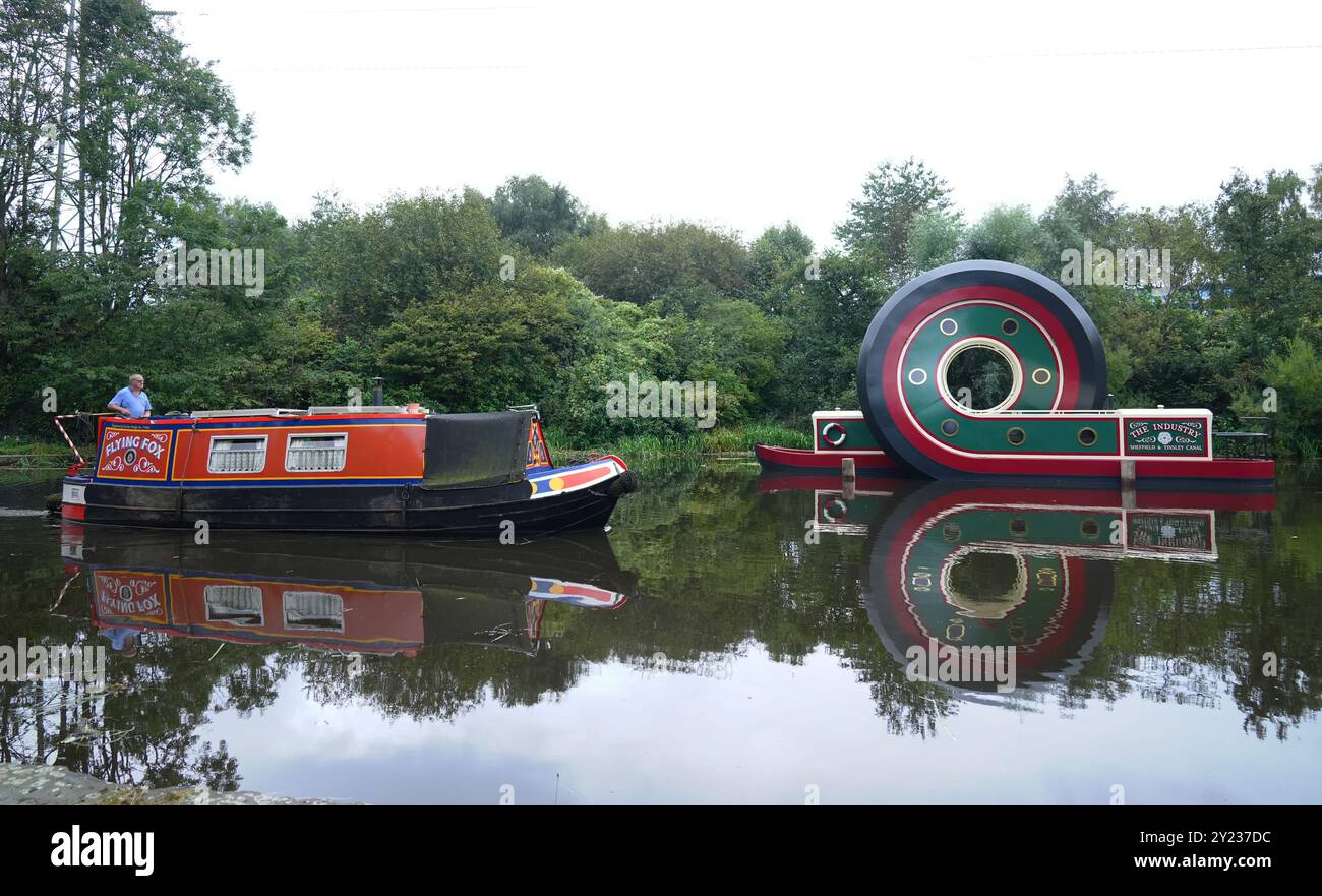 A canal boat passes the new sculpture of a canal boat after it was ...