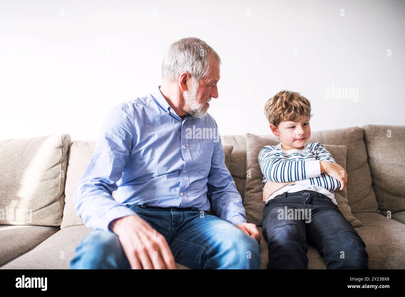 Grandpa is arguing with his grandson. Angry boy sitting on sofa ...