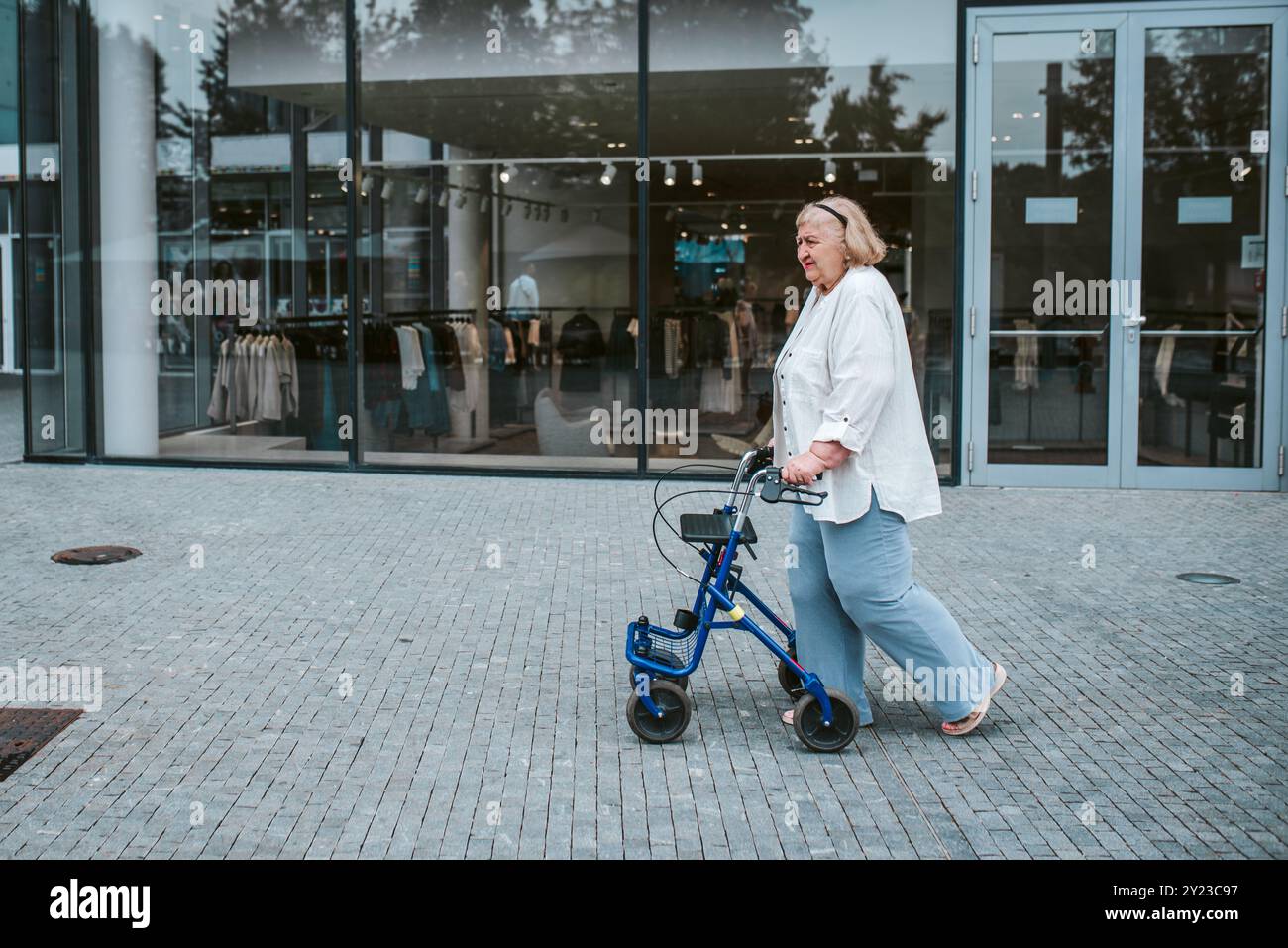 Elderly woman walking on city street with rollator, running errands ...