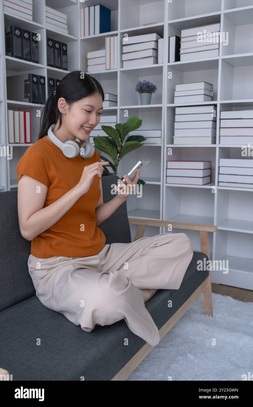 woman relaxes at home, reclining on the sofa with her smartphone ...