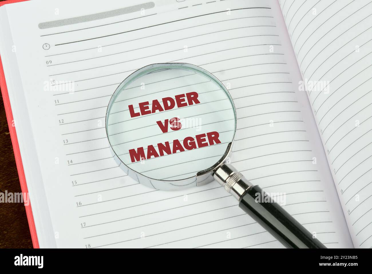 Leader vs manager is shown through a magnifying glass on a blank page ...