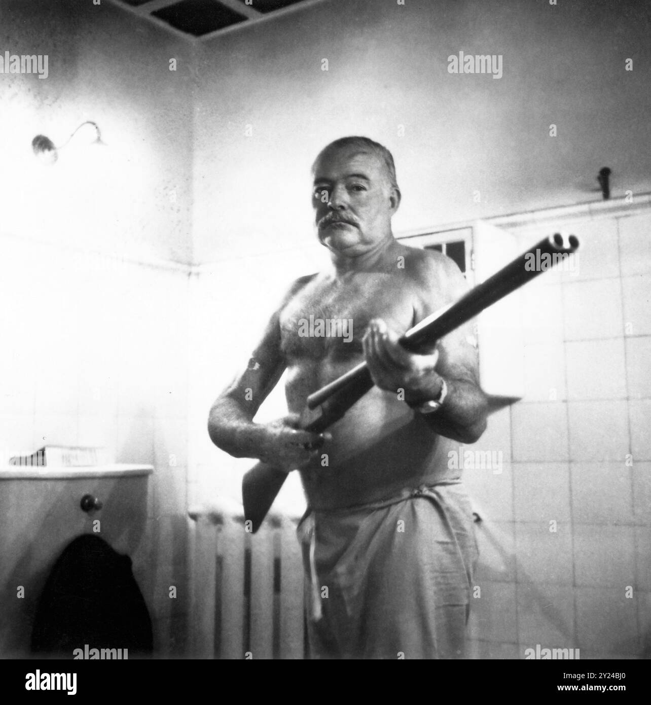 Photograph of Ernest Hemingway holding a shotgun in the Finca Vigia ...