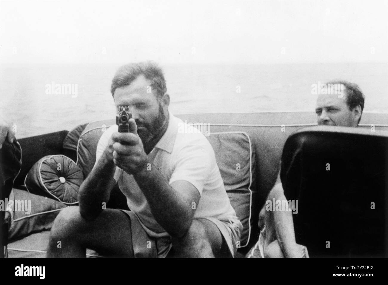Photograph of Ernest Hemingway, holding a tommy gun, aboard his yacht ...