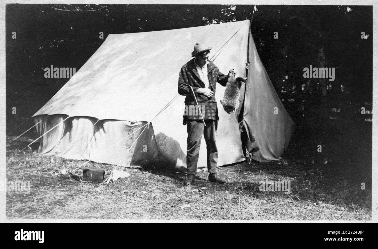 Ernest Hemingway, standing in front of tent, carrying a gun and ...