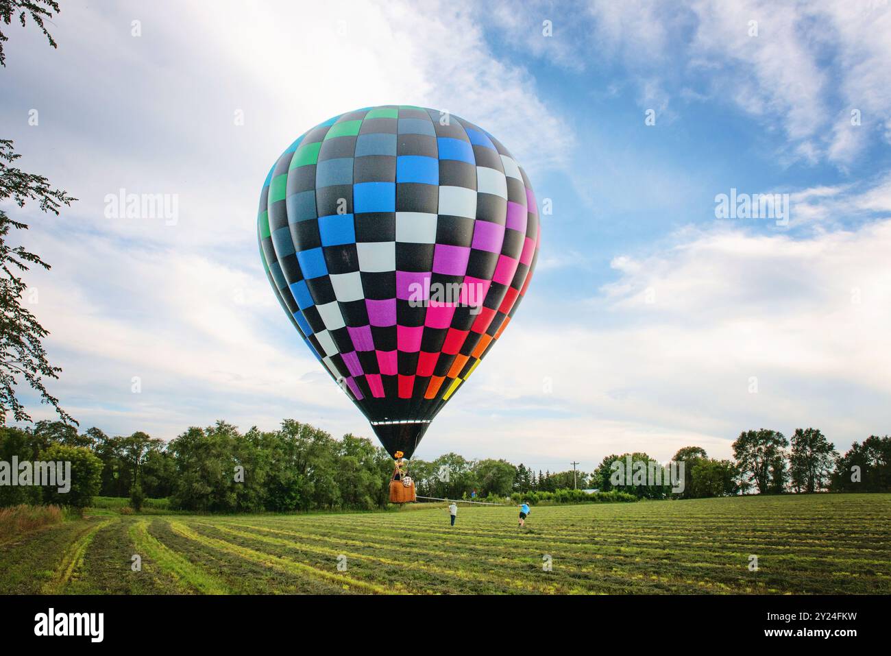 Hot air balloon landing in a field Stock Photo - Alamy