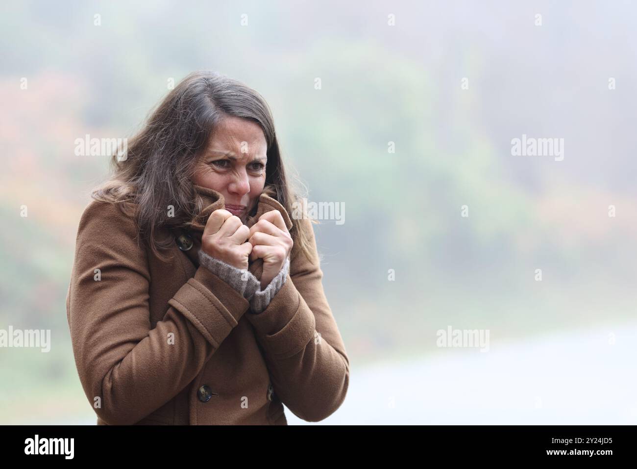 Middle aged woman getting cold grabbing jacket alone in winter Stock ...