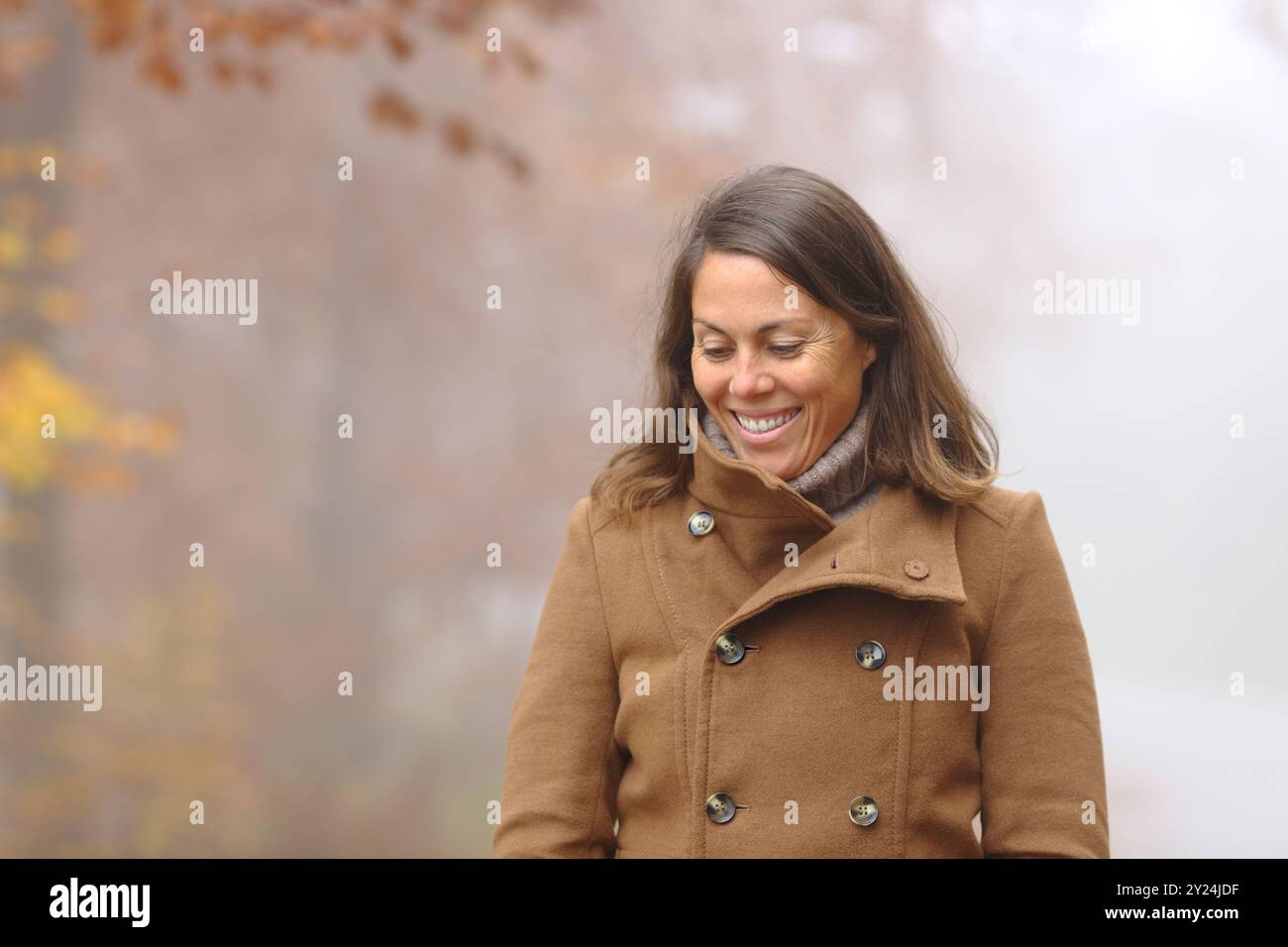 Happy middle aged woman walking and smiling in a park in winter Stock ...