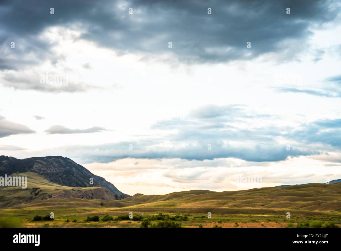 Rolling hills and distant mountains under a cloud-filled sky Stock ...