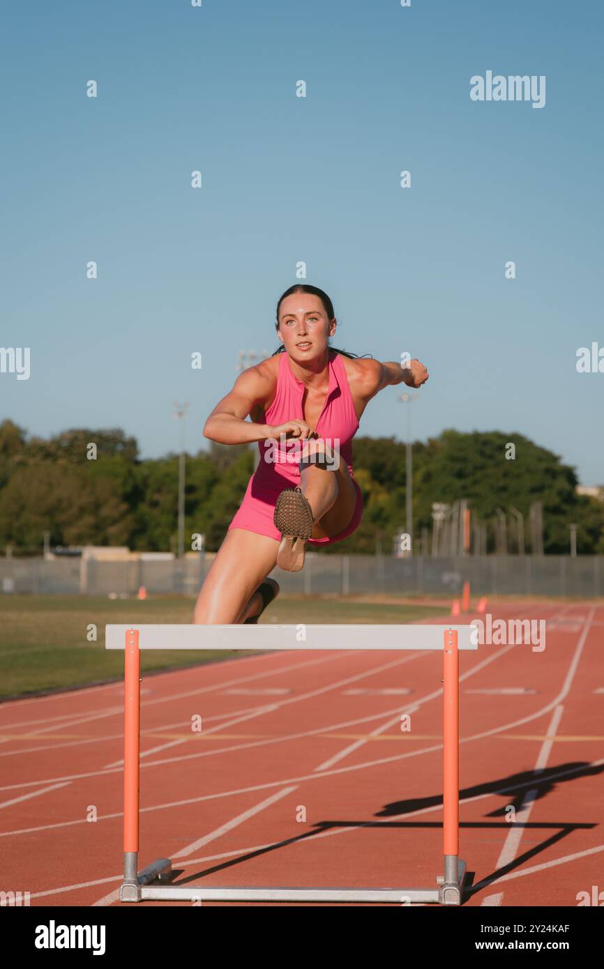 Female track athlete hurdling on track Stock Photo - Alamy