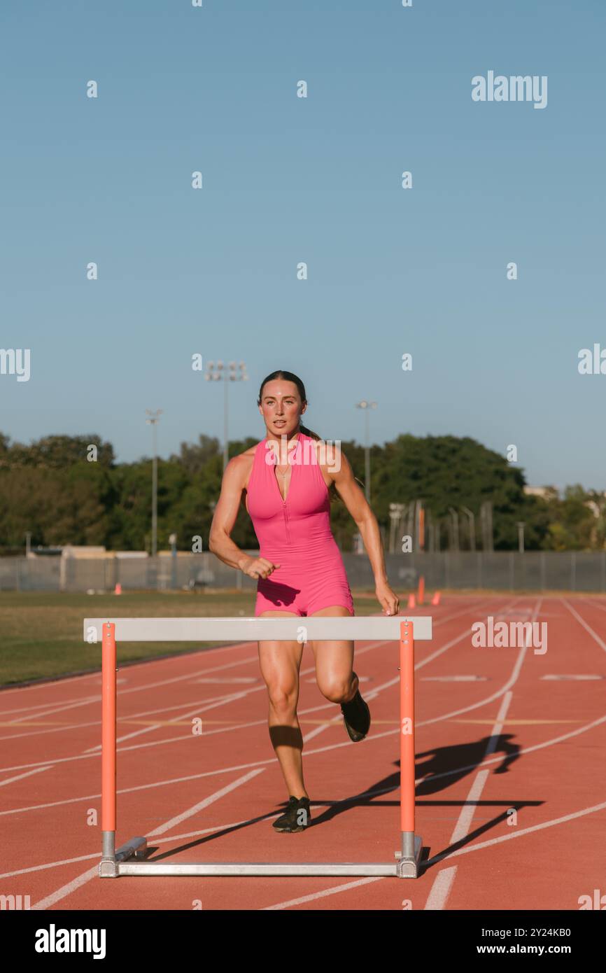 Female track athlete about to jump over hurdle Stock Photo - Alamy