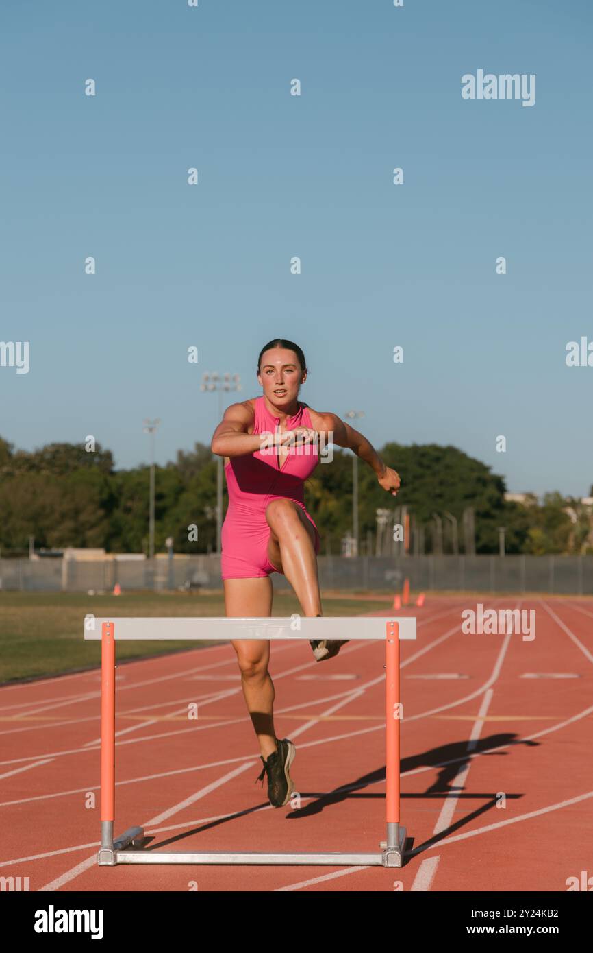 Female track athlete about to go over hurdle on track Stock Photo - Alamy