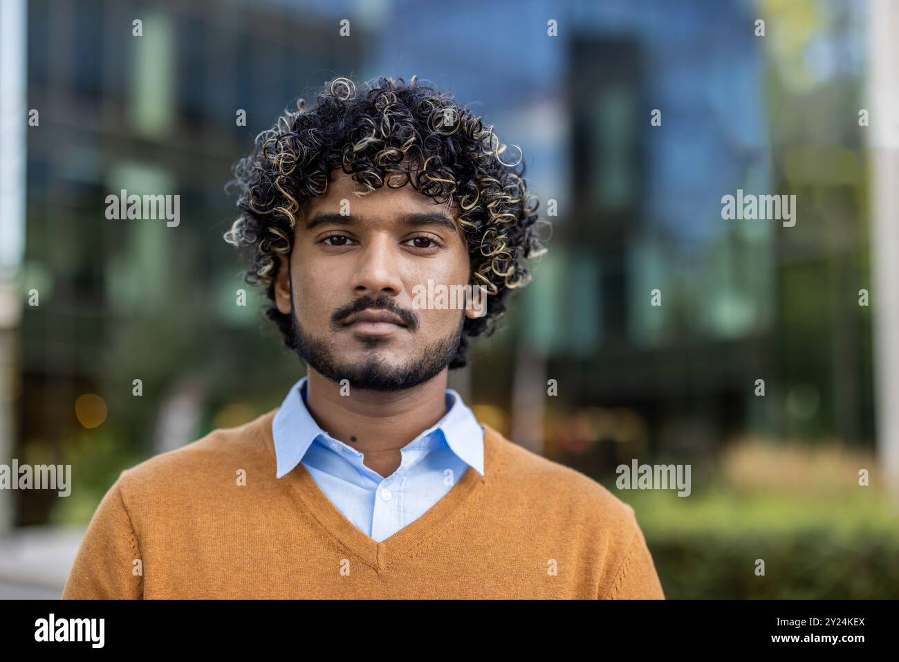 Confident young professional with curly hair standing outside office ...