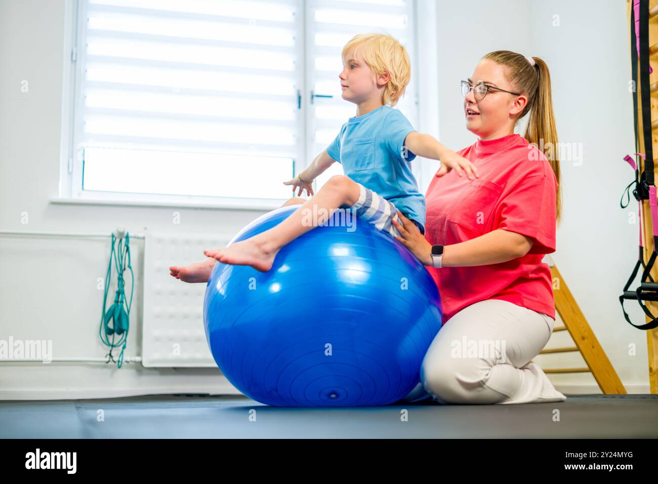 Young boy with female physical therapist exercising during therapy ...