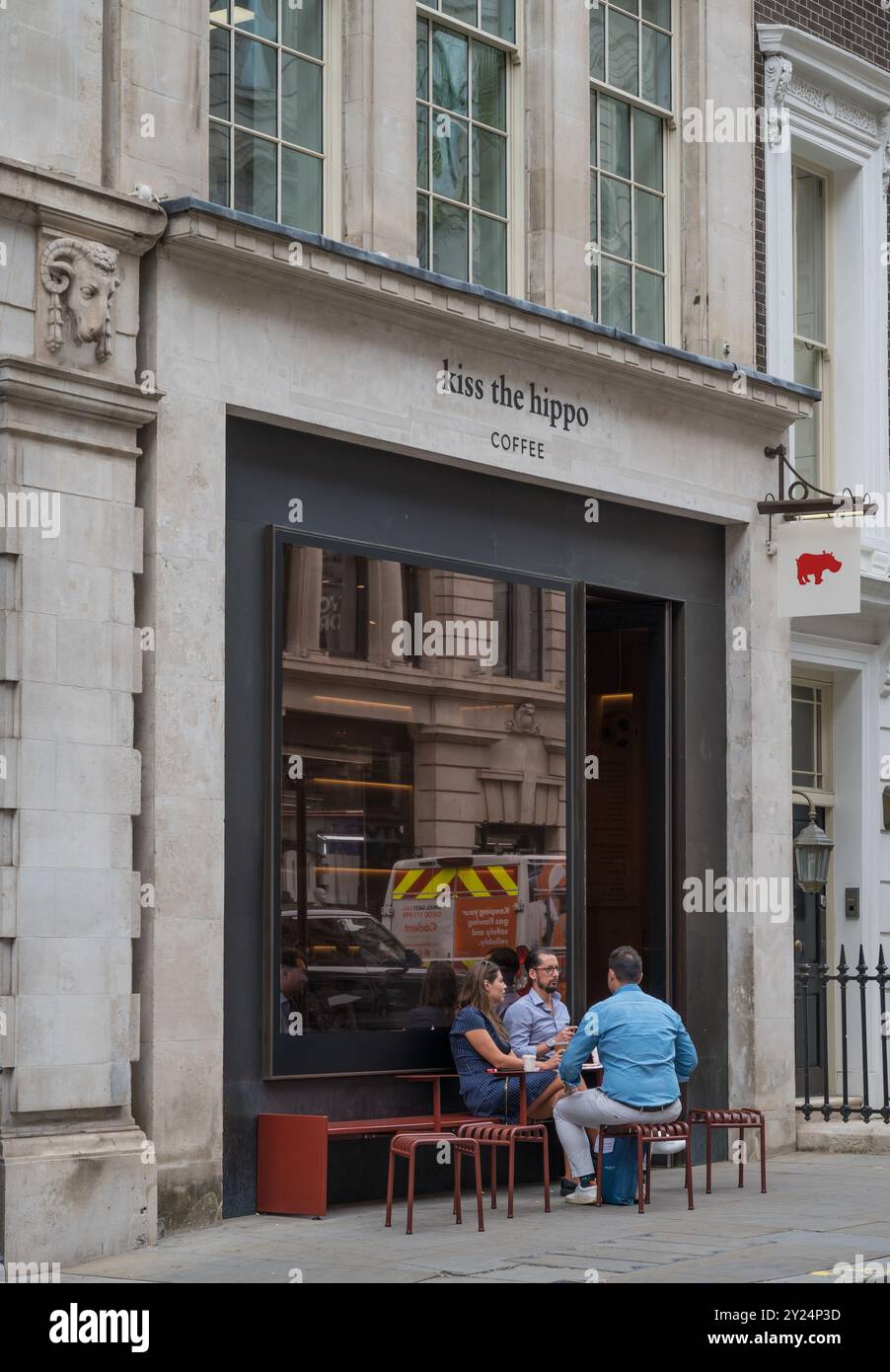 Two men and a woman take refreshment seated at pavement table outside ...