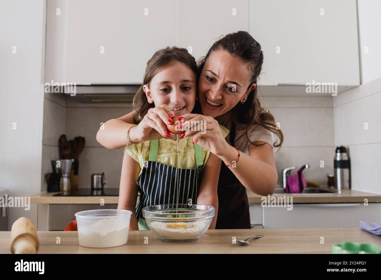 Mom and girl opening an egg, following a recipe Stock Photo - Alamy