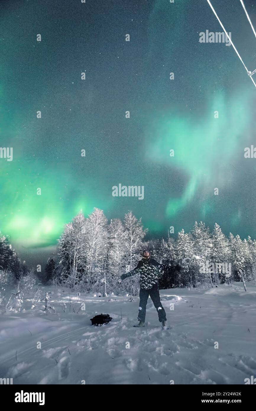 Man stood with arms out under the northern lights in Rovaniemi, Lapland ...