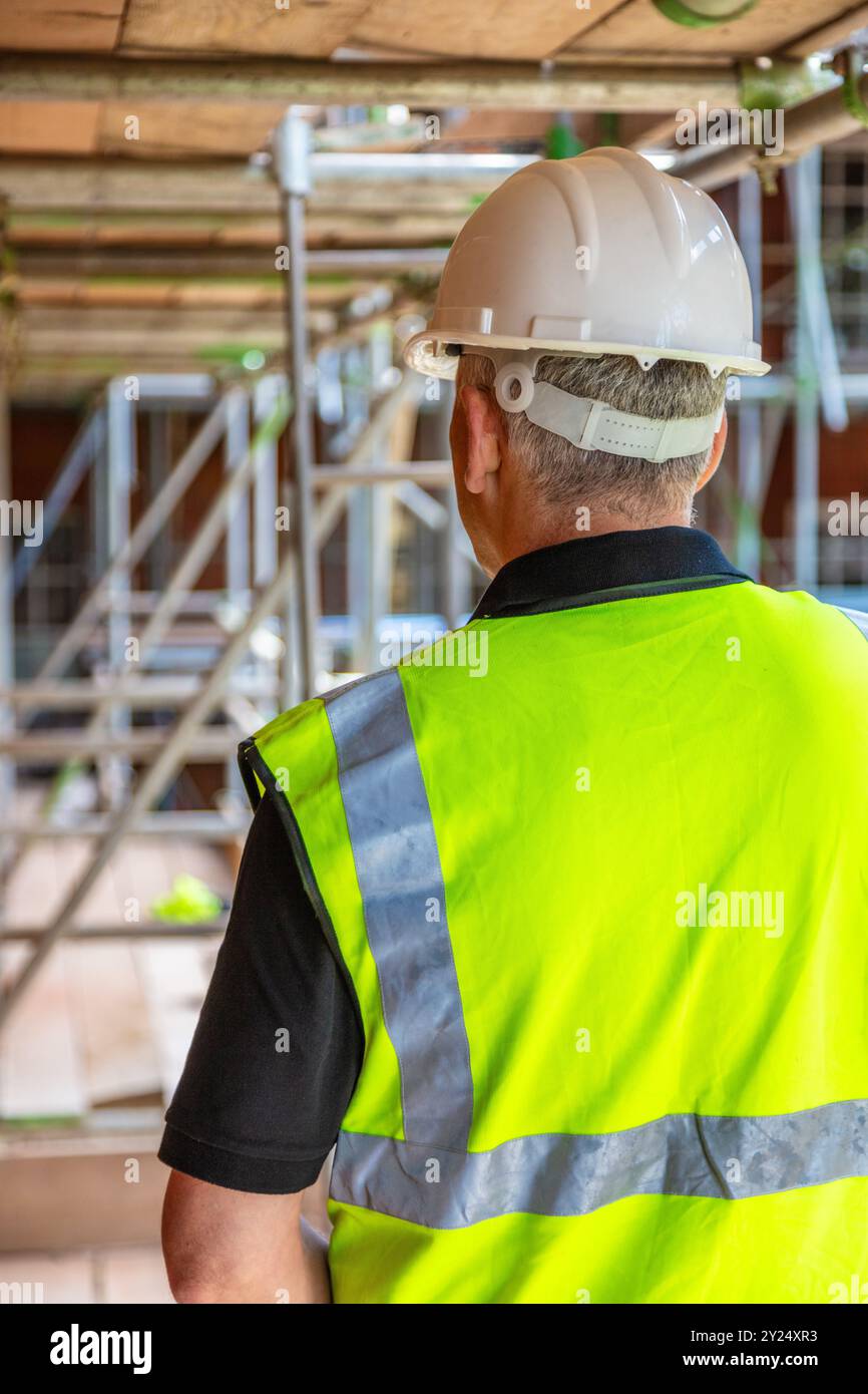 Rear view of male builder construction worker on building site wearing ...