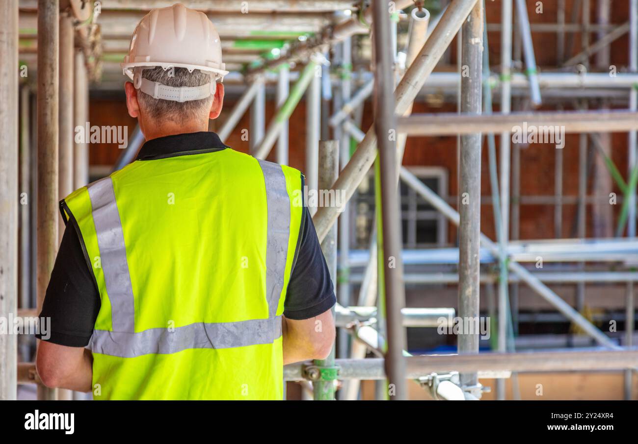 Rear view of male builder construction worker on building site wearing ...
