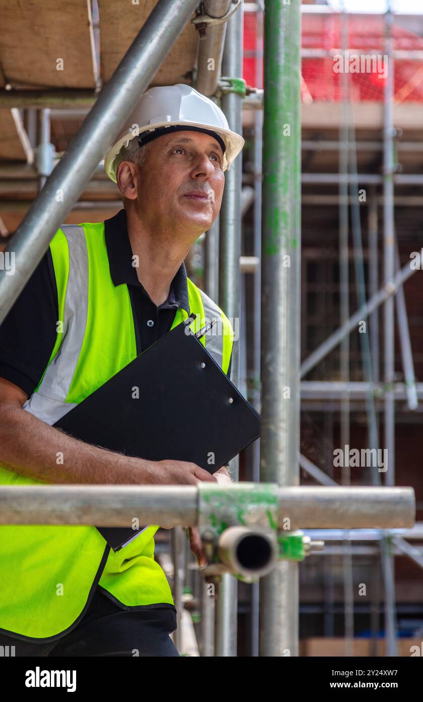 Male builder, construction worker or site manager holding a clipboard ...