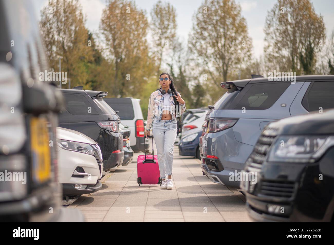 Indian woman in stylish denim outfit with pink suitcase, traveling to ...
