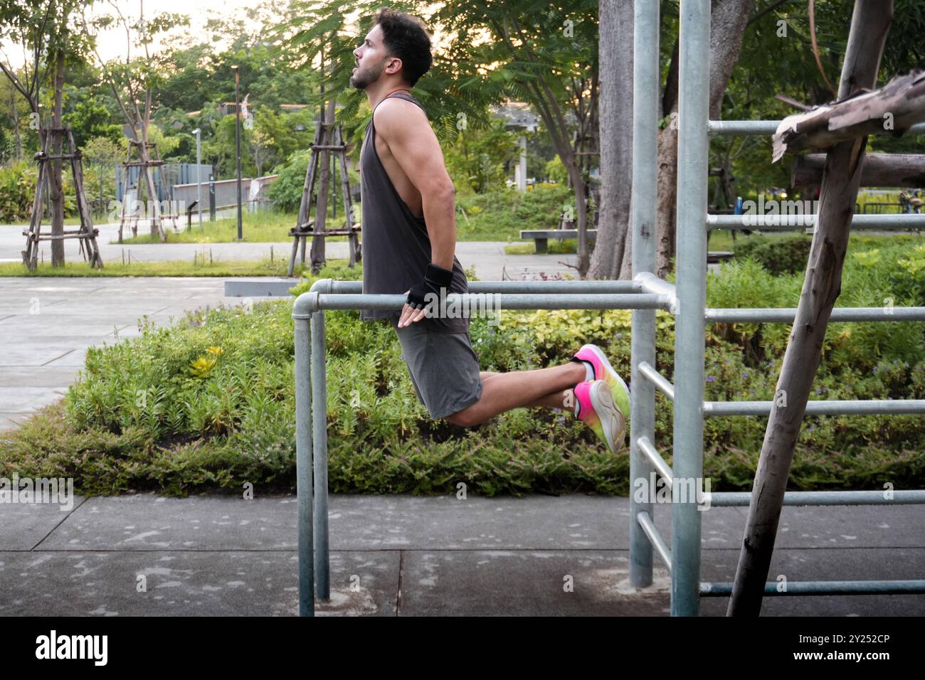 Side view of a young man doing calisthenics in a park in the center of ...