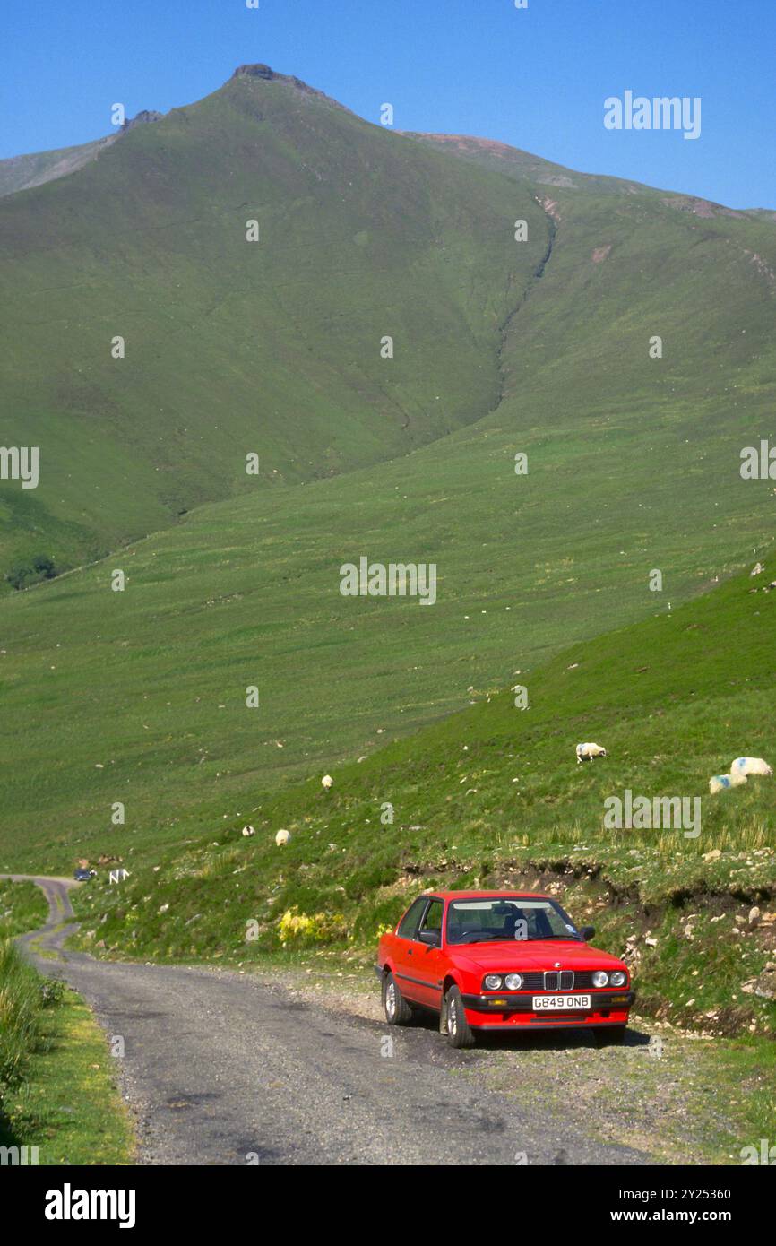 Car on mountain road with peak of Caherconcree behind, Dingle Peninsula ...