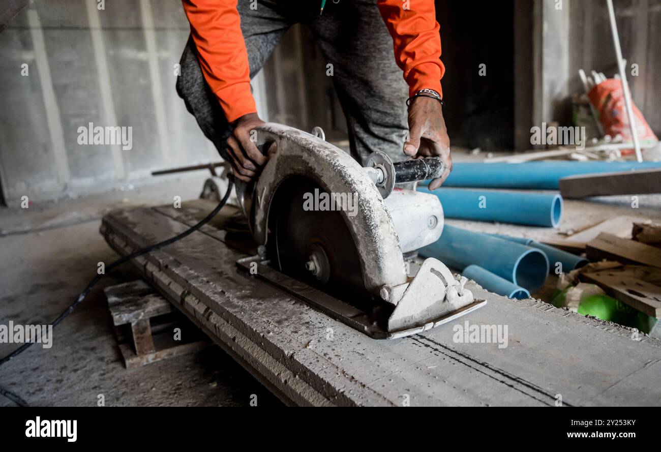 A builder using a circular saw to cut a large concrete piece Stock ...