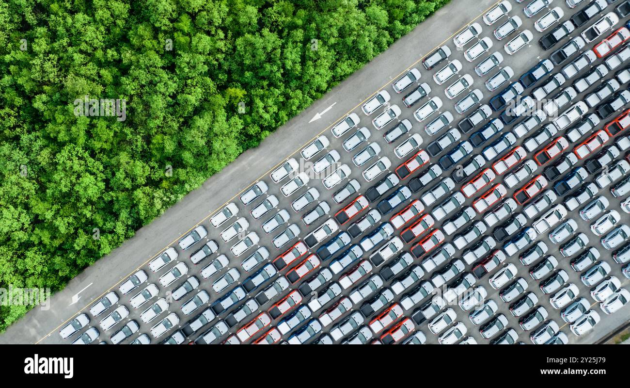 Aerial view of a factory parking lot filled with new cars adjacent to ...