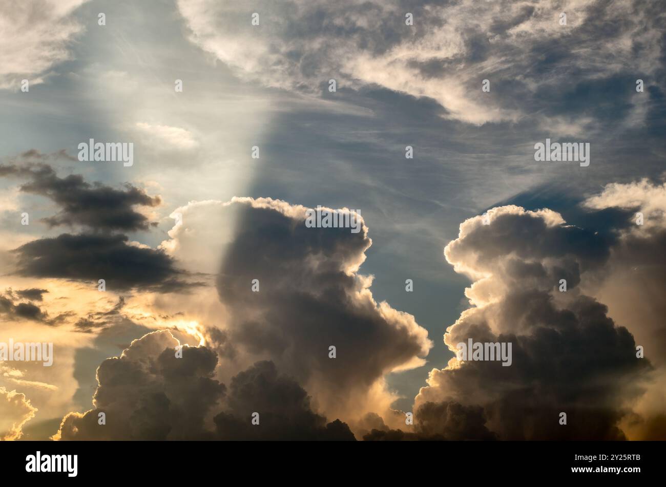 Sunset sky with a sunbeam behind the dark clouds, hidden sun. Dramatic ...