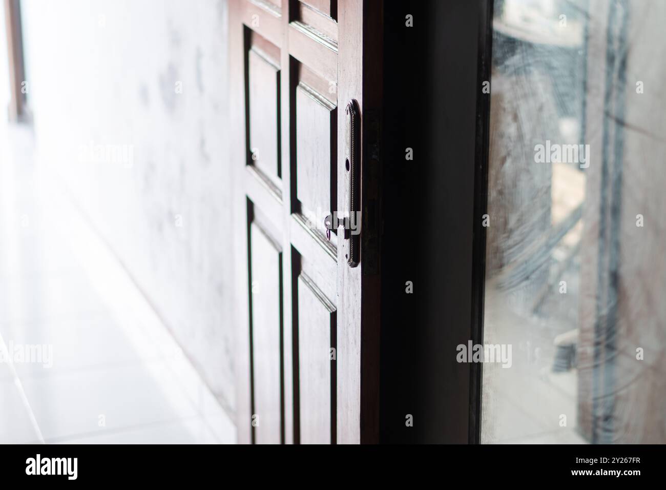 A partially open wooden door with a sleek handle, revealing a glimpse ...