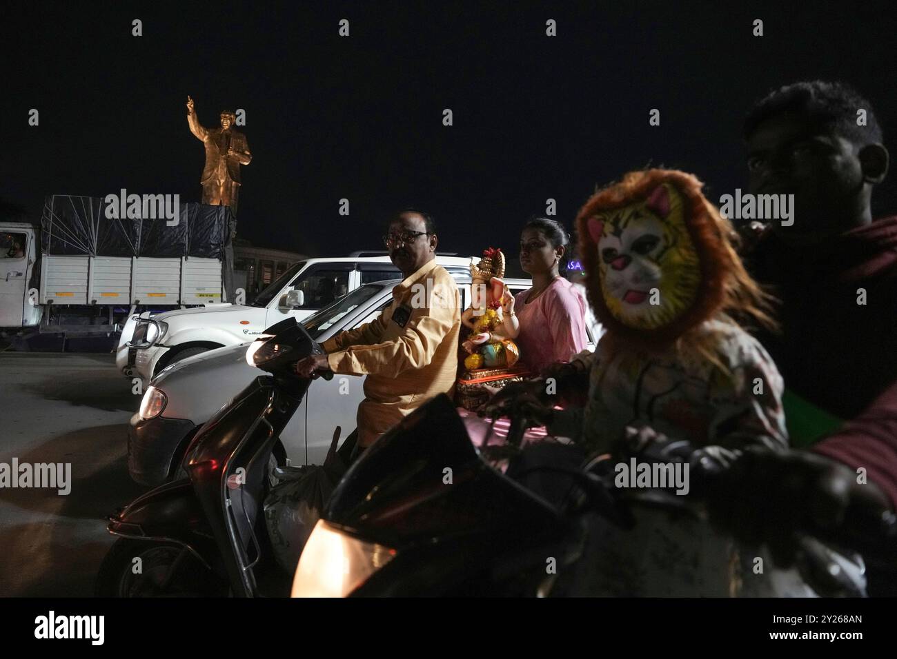 People carry an idol of elephant-headed Hindu God Ganesha on a bike to immerse it in Hussain ...
