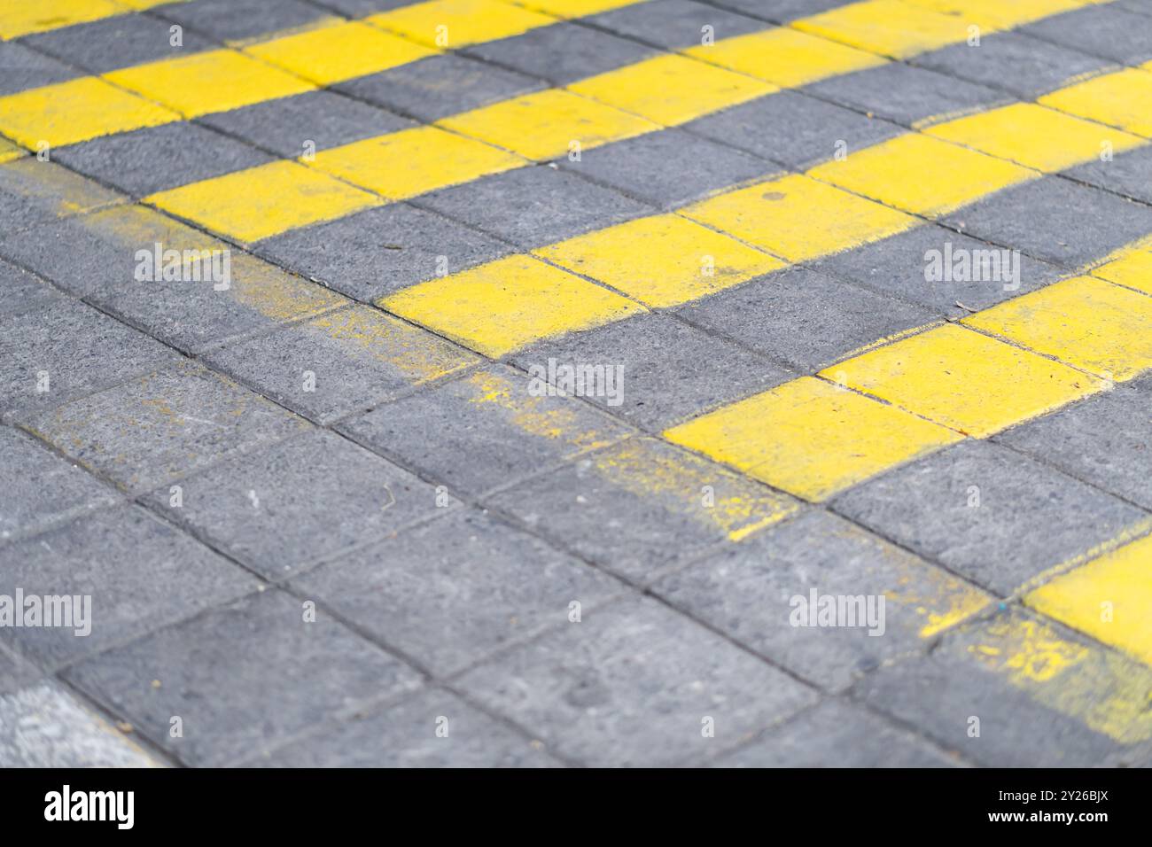 Close-up view of a pedestrian crosswalk with yellow stripes on gray ...