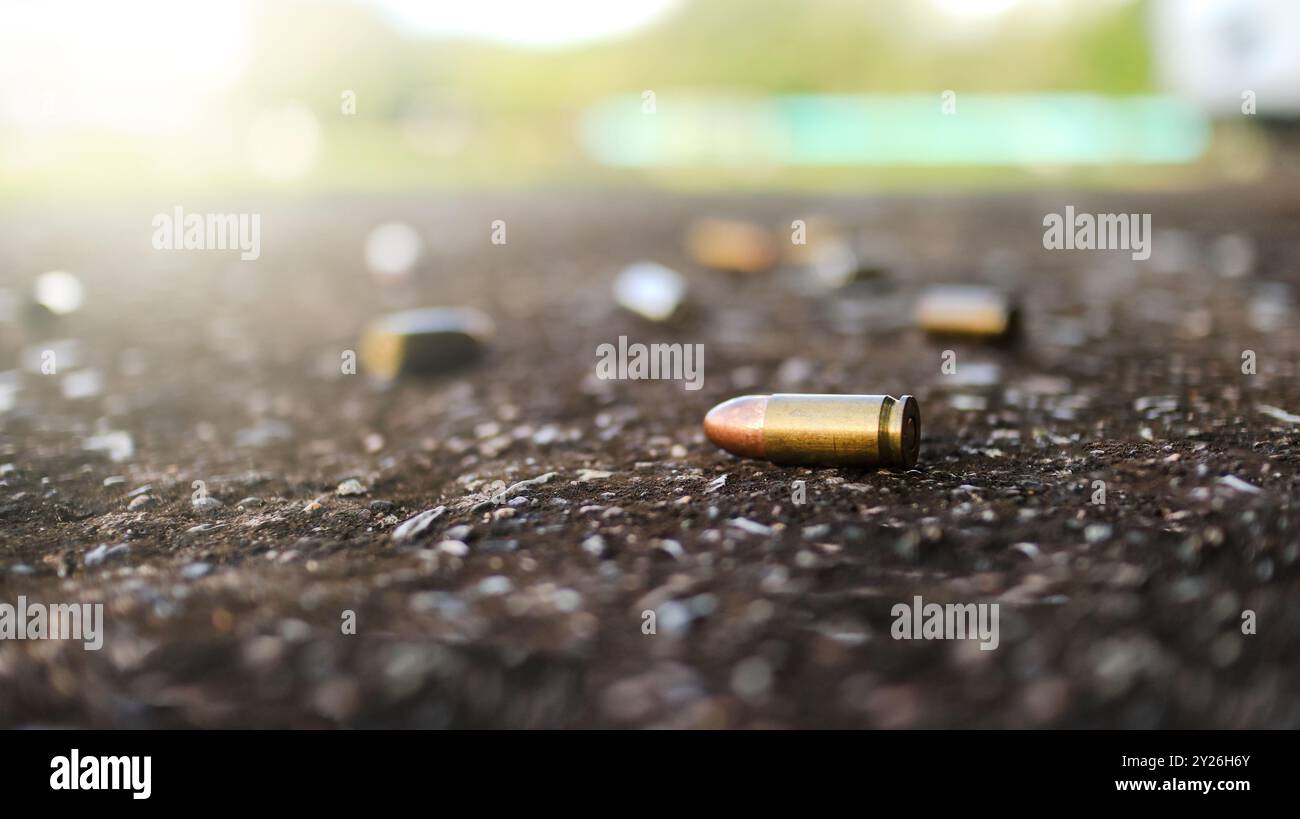 Spent bullet casing lying on dark ground with blur number 2 sign ...