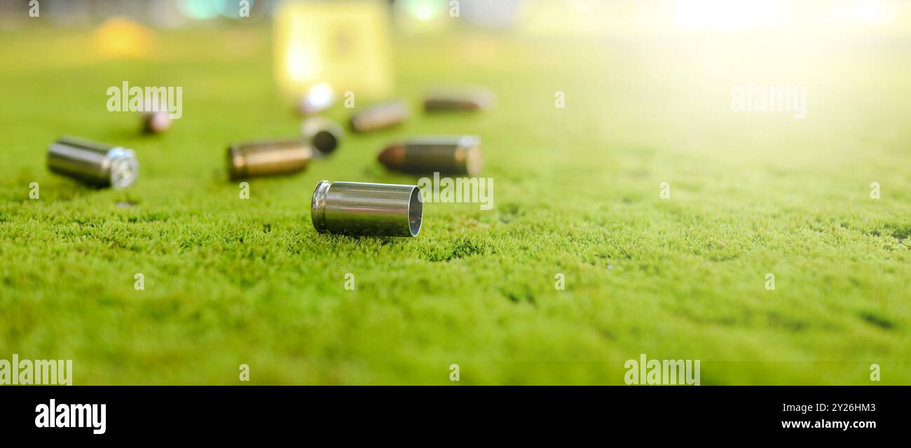 Spent bullet casing lying on the green ground with blur number 2 sign ...