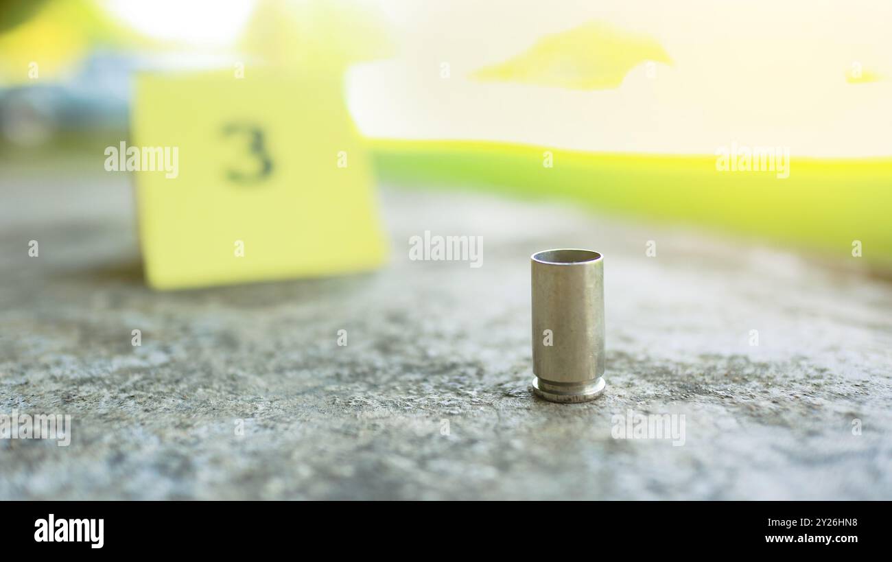 Spent bullet casing lying on dark ground with blur number 3 sign ...
