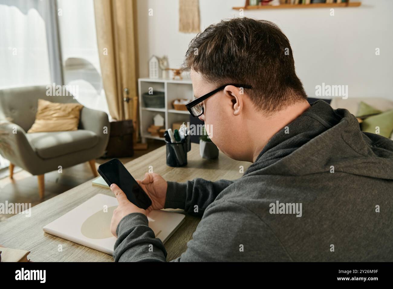 A young man with Down syndrome enjoys browsing his phone while seated ...