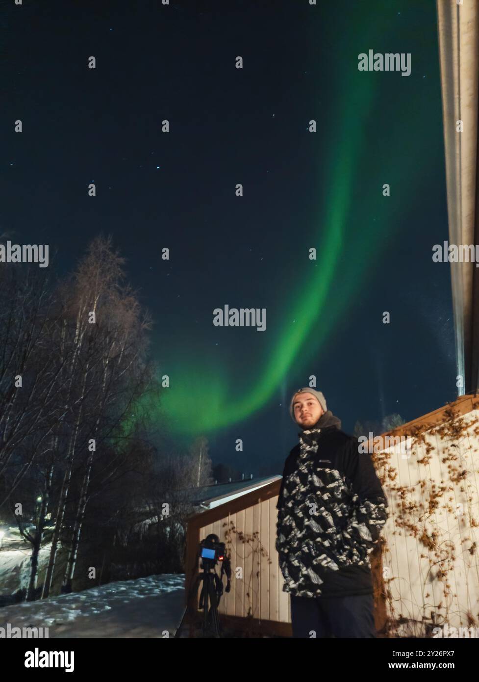 Man under strong northern lights outside house in Rovaniemi, Lapland ...