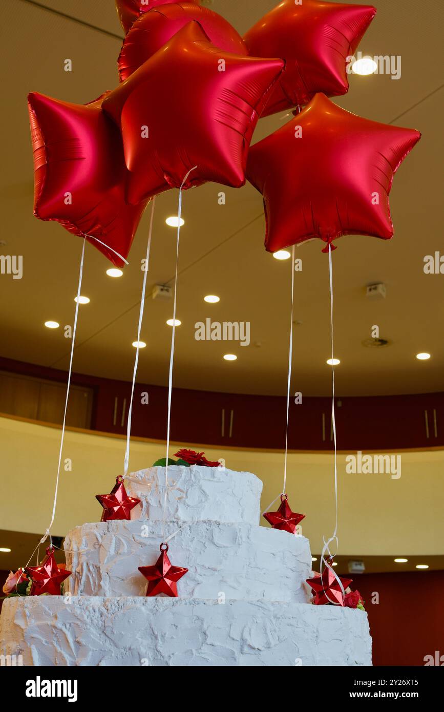 Five pink balloons and a giant concrete birthday cake in a city hall ...